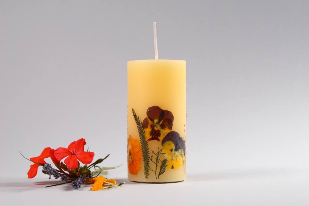 Kézzel készített árvácskával díszített sárga gyertya, mézes akác illattal.